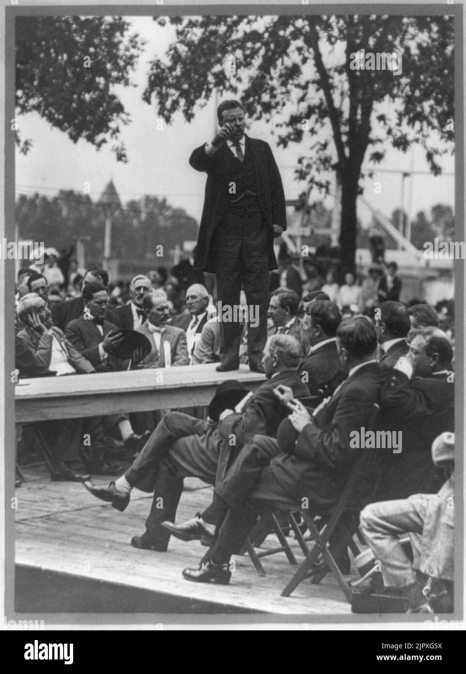 Theodore Roosevelt standing on table outdoors and making speech to men ...
