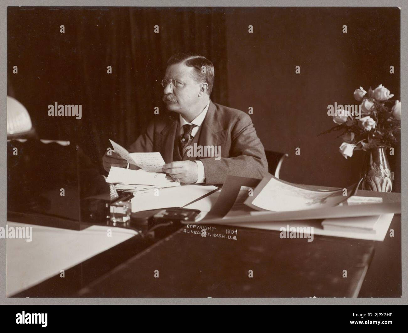 Theodore Roosevelt, head-and-shoulders portrait, seated at desk holding ...