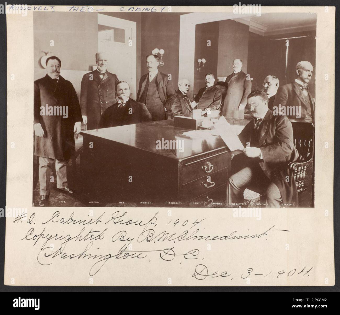 Theodore Roosevelt, seated at desk reading, surrounded by cabinet ...
