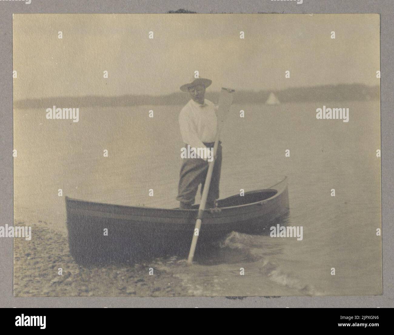 Theodore Roosevelt, standing up in canoe, pushing away from shore with ...