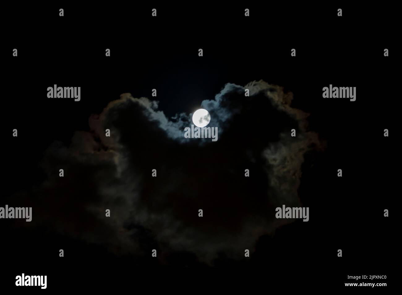 A beautiful night skyscape of the full moon glowing behind clouds Stock ...