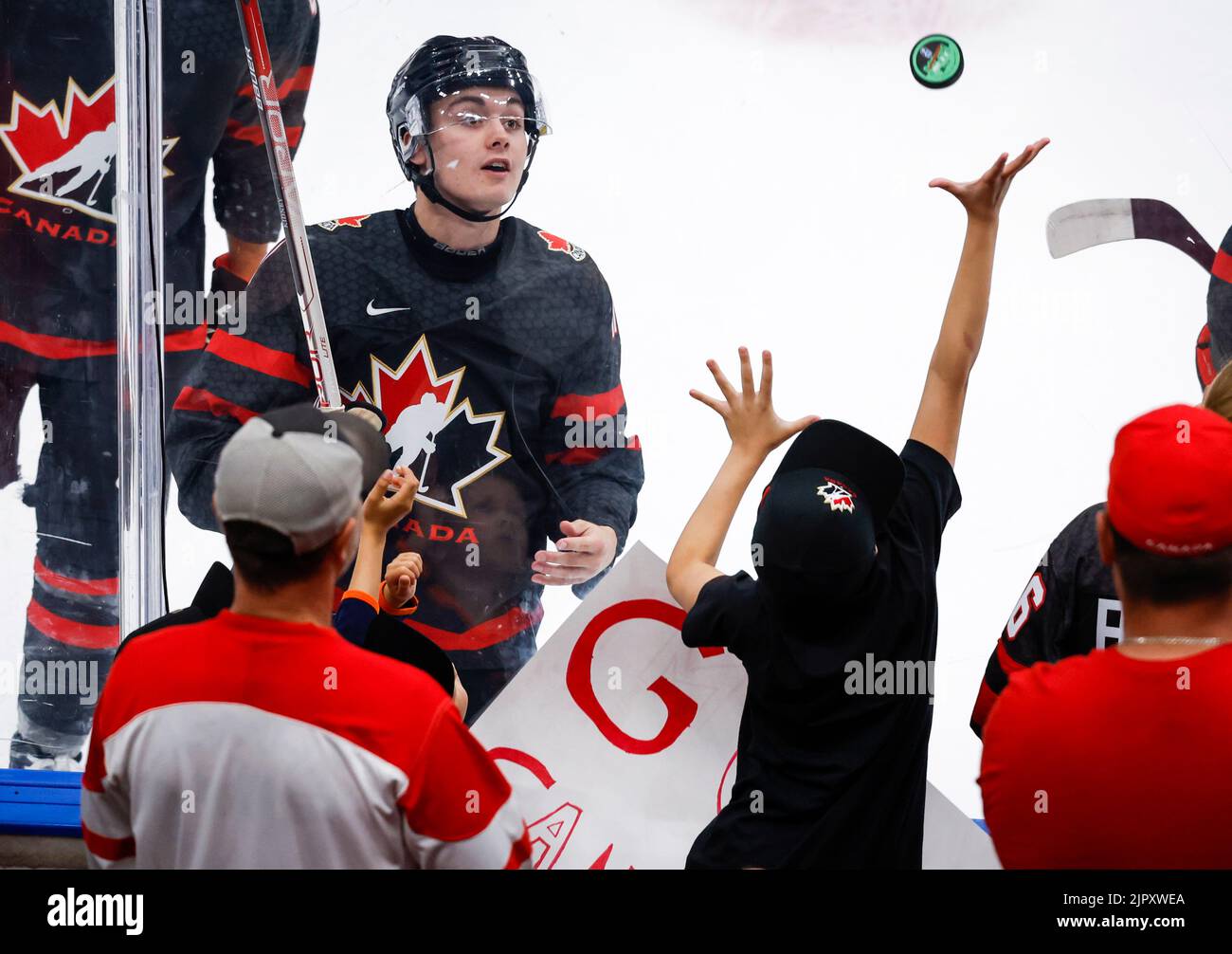 Team Canada forward Riley Kidney, left, tosses a puck to a young fan ...