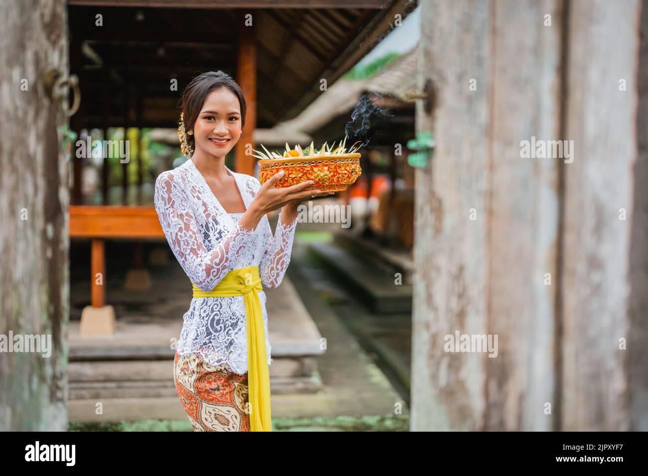 beautiful smiling balinese woman looking at camera while carrying ...
