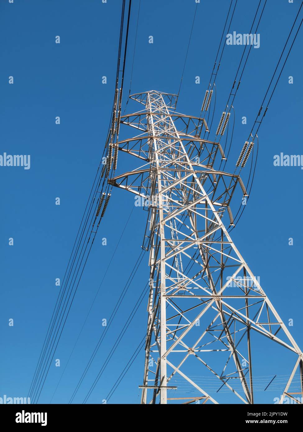 Low angle view of an electricity transmission pylon against blue sky ...