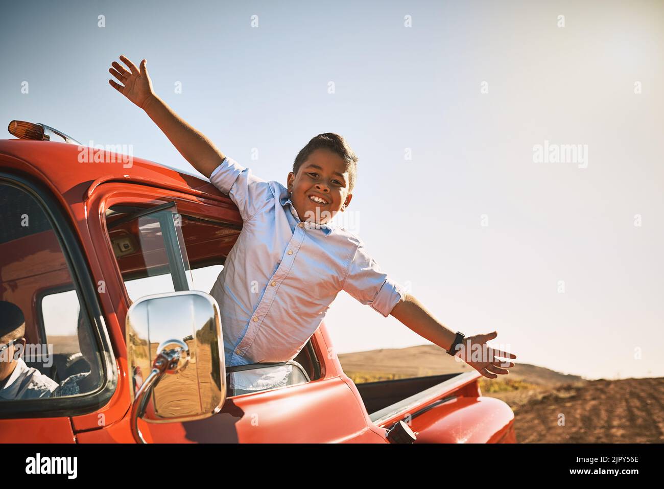 Take on life with open arms. a young cheerful boy leaning out of a red ...
