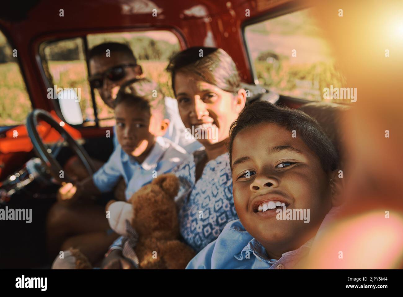 Smile for the camera mom and dad. a cheerful young family driving in a ...