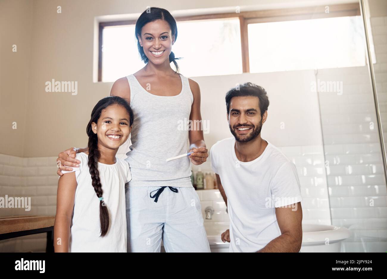 Soon to be a happy family of four. Portrait of parents showing their ...