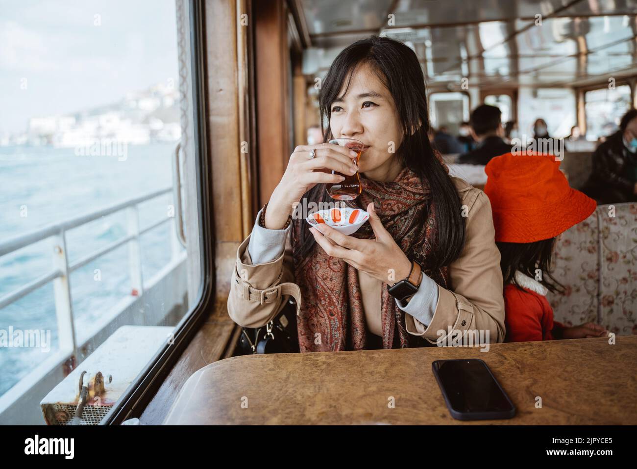 woman sitting on a ferry boat having turkish tea Stock Photo - Alamy