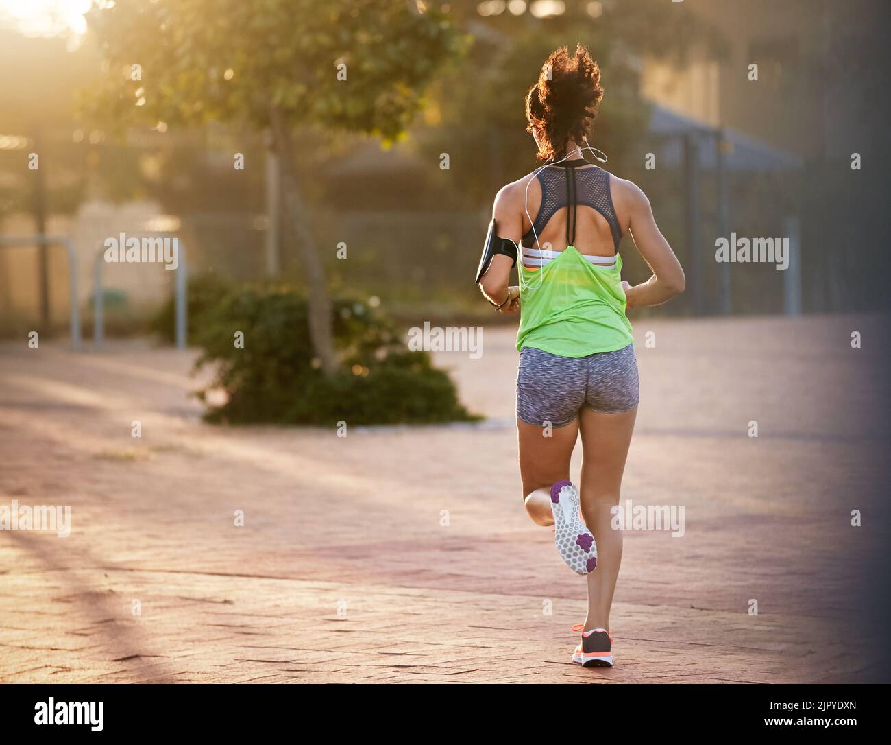 Going the distance. Rear view shot of a sporty young woman out for a ...
