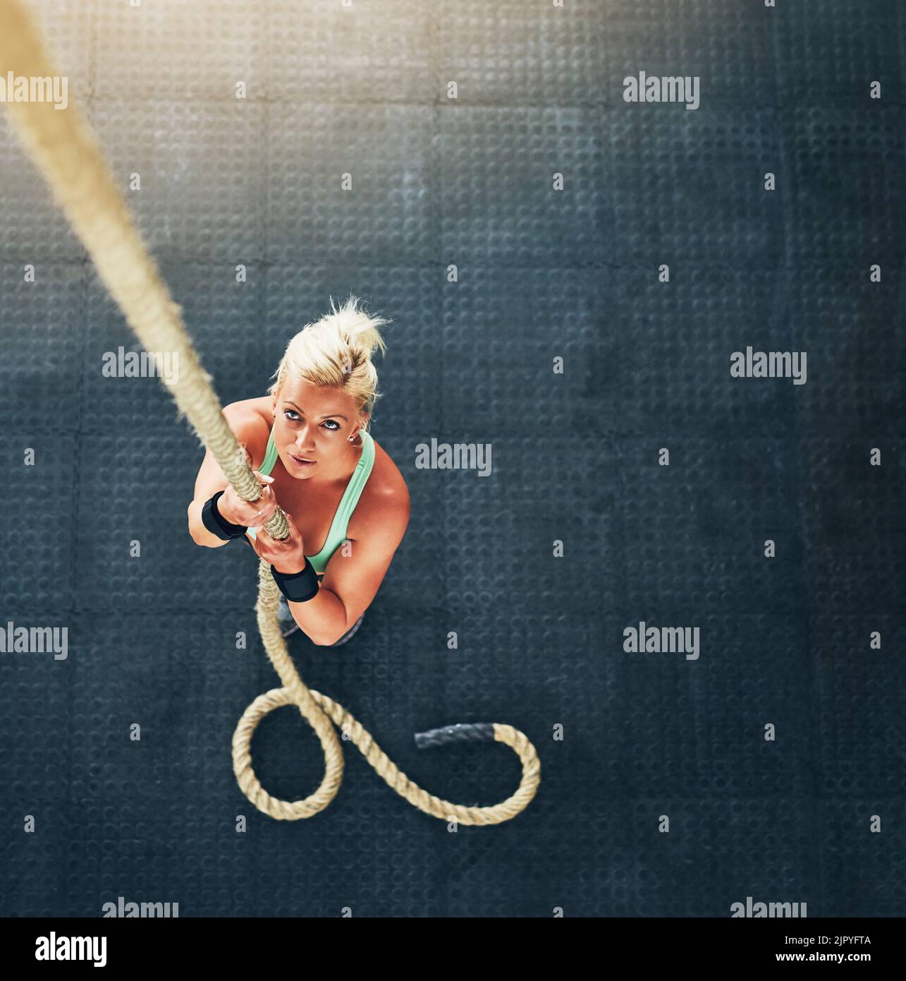 Working her way to a firm and fit body. a sporty young woman climbing a ...