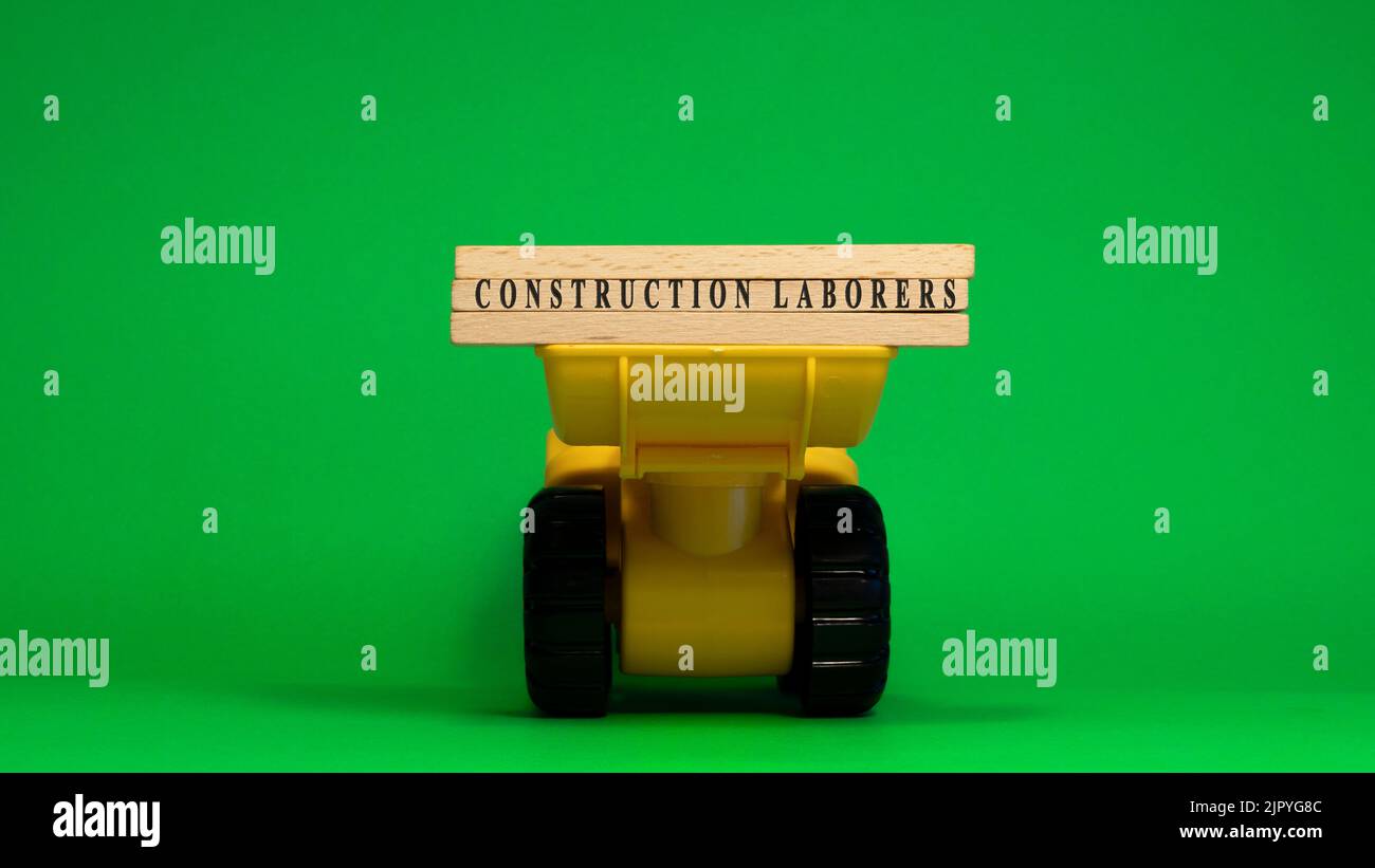 The word Construction laborers is written on wooden sticks. Machine ...