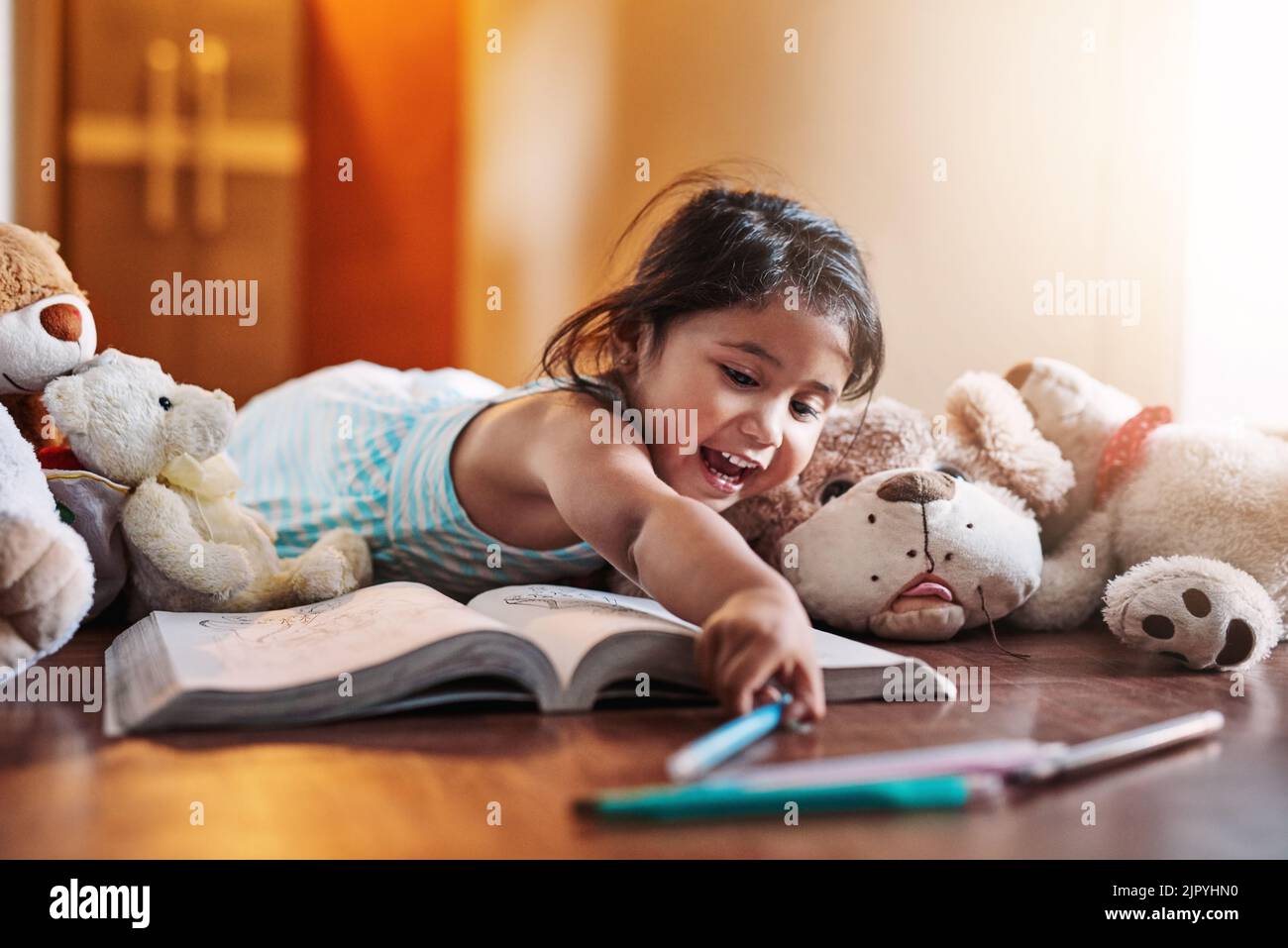 I can almost reach it. a focused little girl writing inside of a book ...