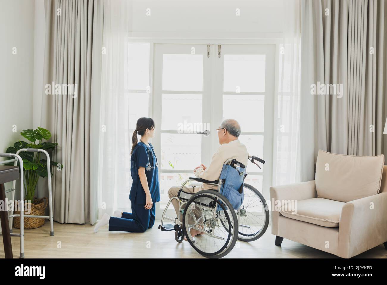 Senior Asian man in wheelchair receives medical help for injury, take ...
