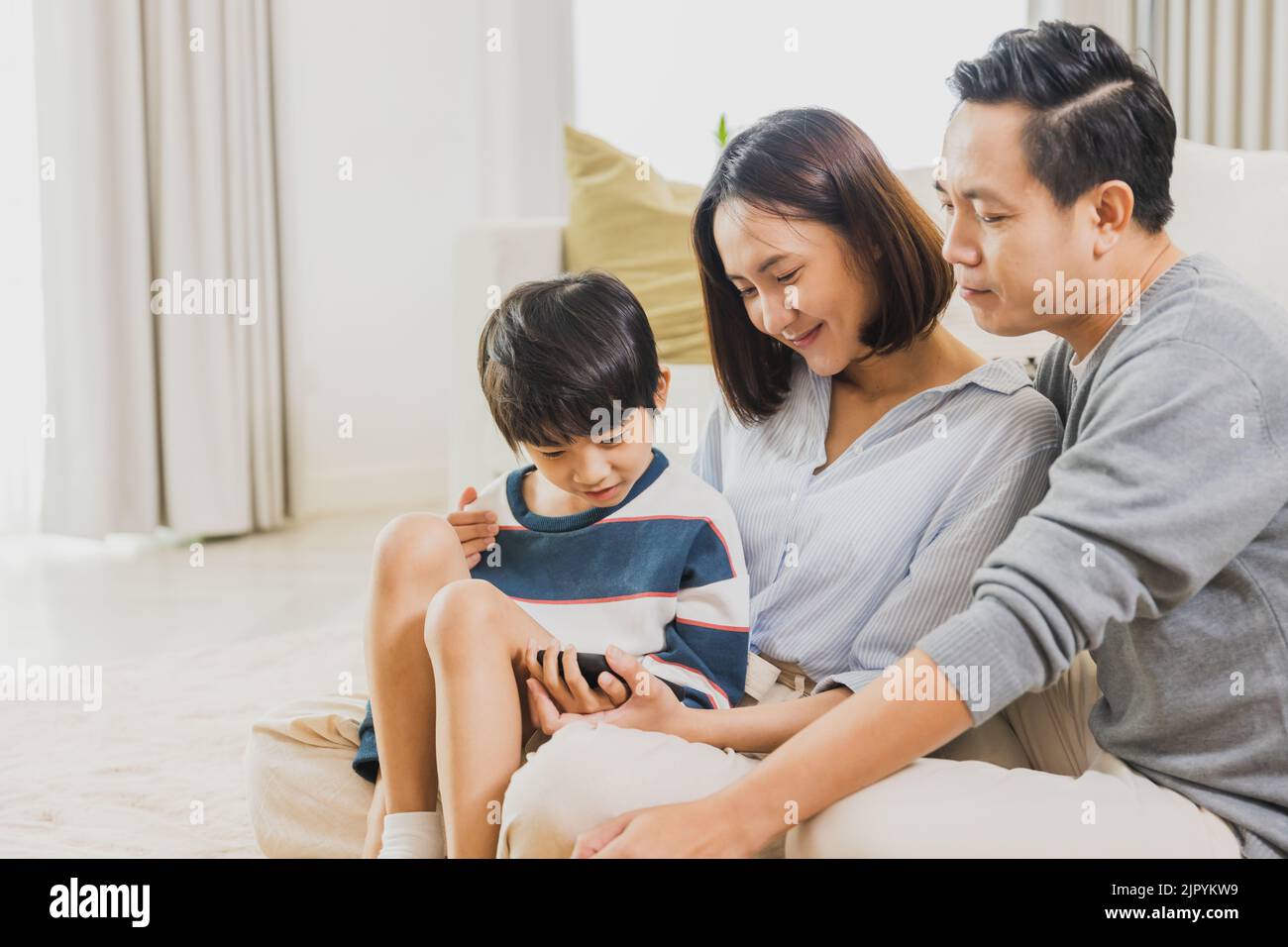 Happy Thai family in house, parents , mom, dad and boy watch on phone Stock Photo - Alamy