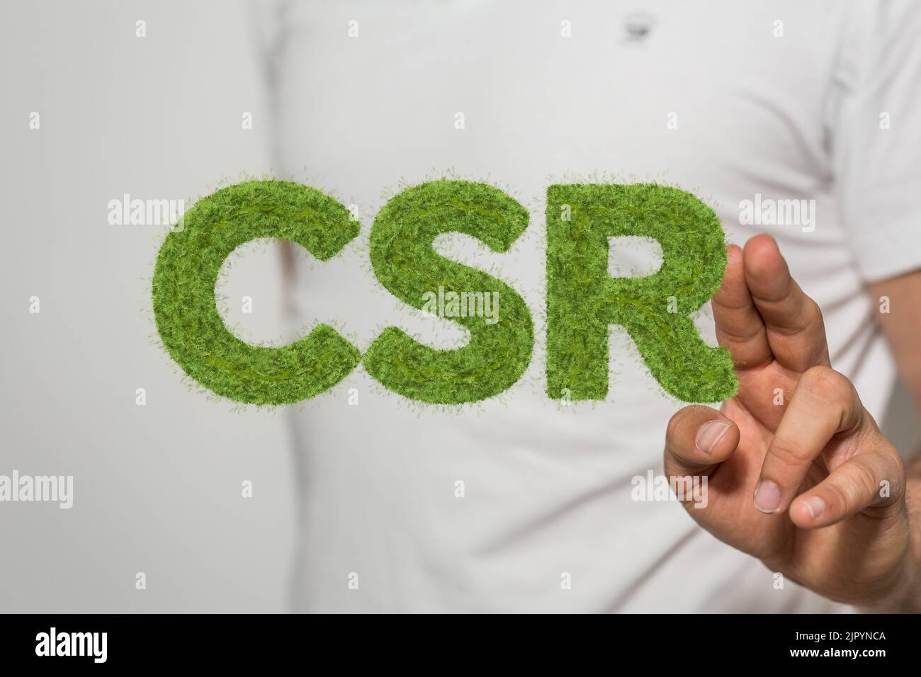 A man's hand pointing to hovering green CSR text Stock Photo - Alamy