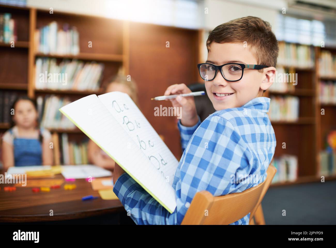 Getting into the work. Portrait of a cheerful young boy doing school ...