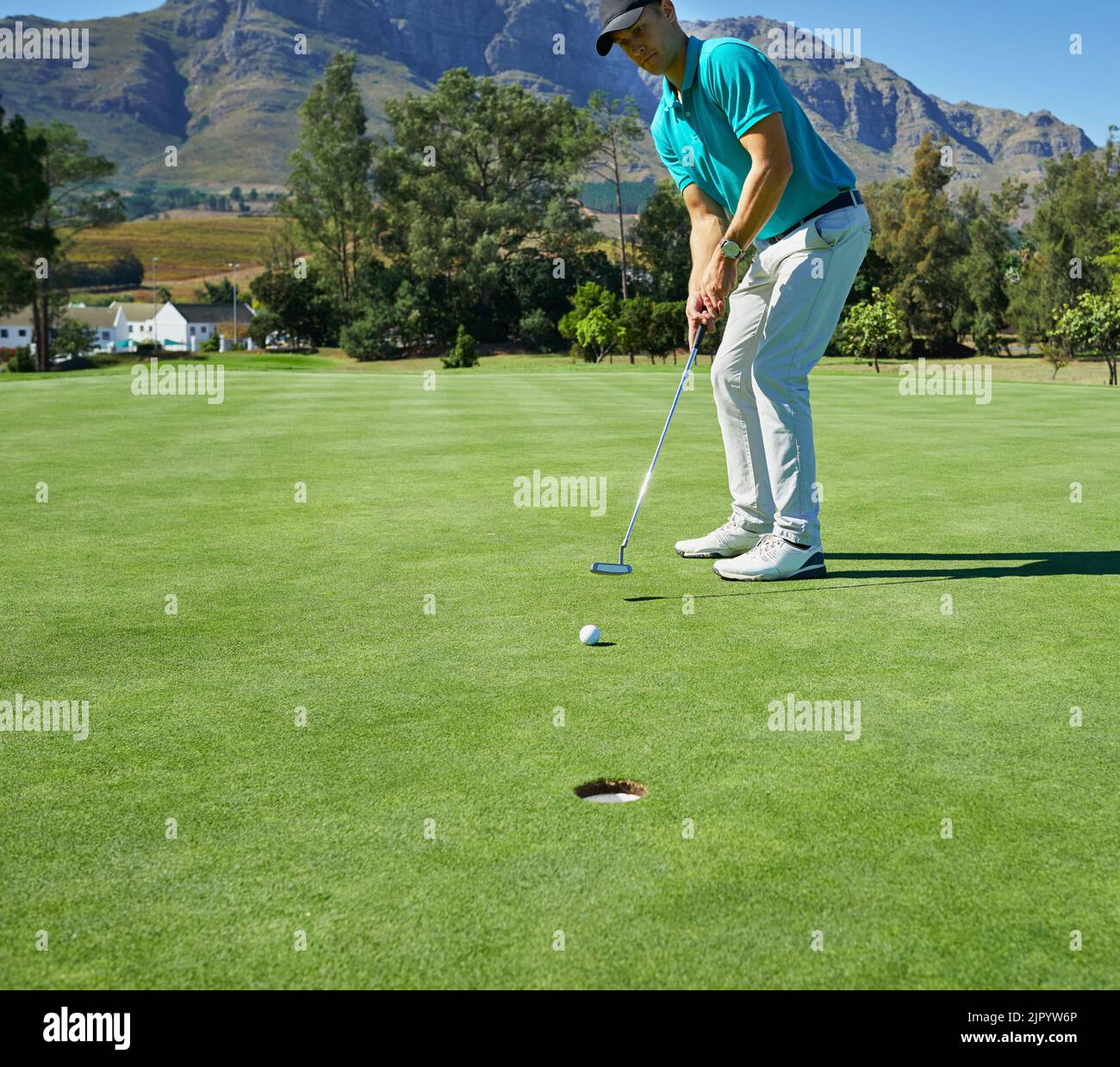 This is going straight in. a focused young man hitting a golfball with ...