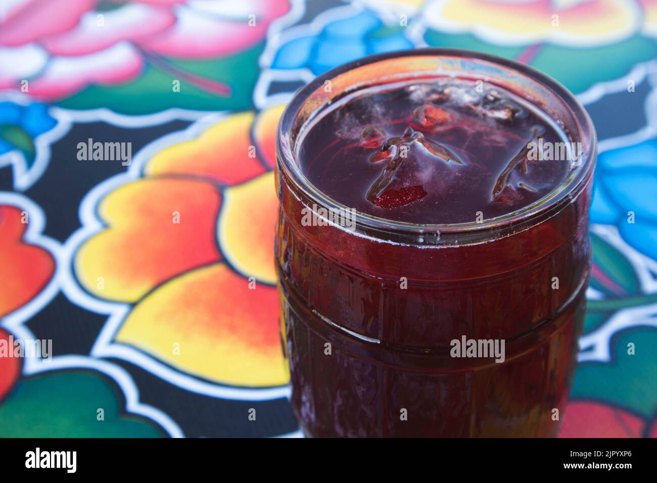 A glass of Jamaica (hibiscus tea) Cocktail made with Mezcal on a table ...