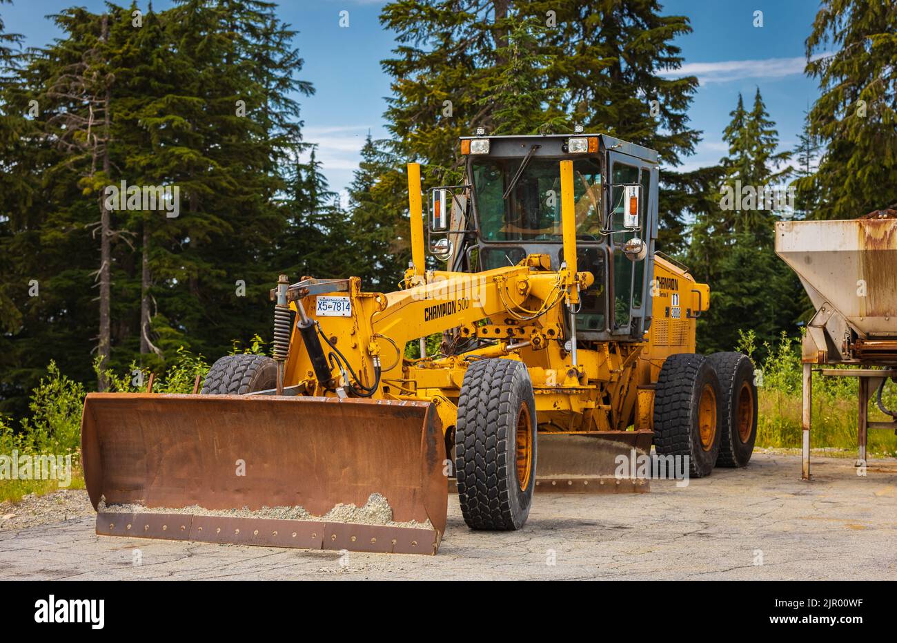 Motor Grader on road construction in forest area. Greyder leveling the ...