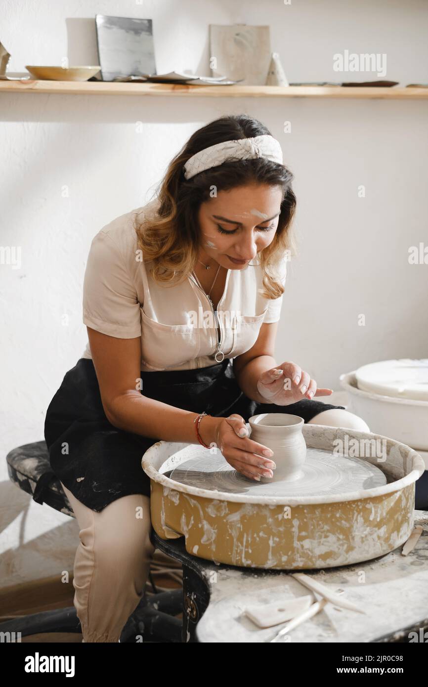 Potter making bowl on wheel. self-employed pottery artist in creative studio working with raw ...