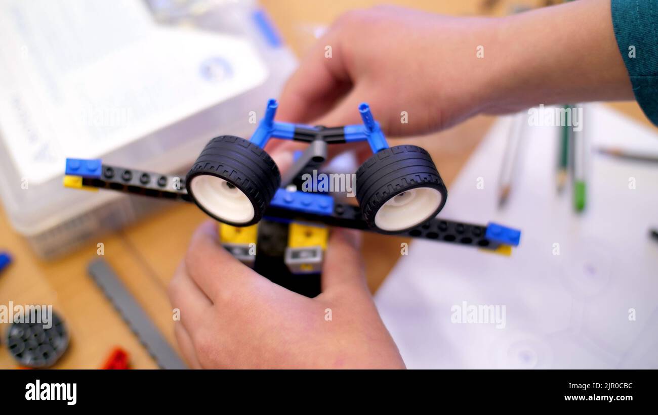 close-up, children's hands hold a multicolored small robot, machine ...