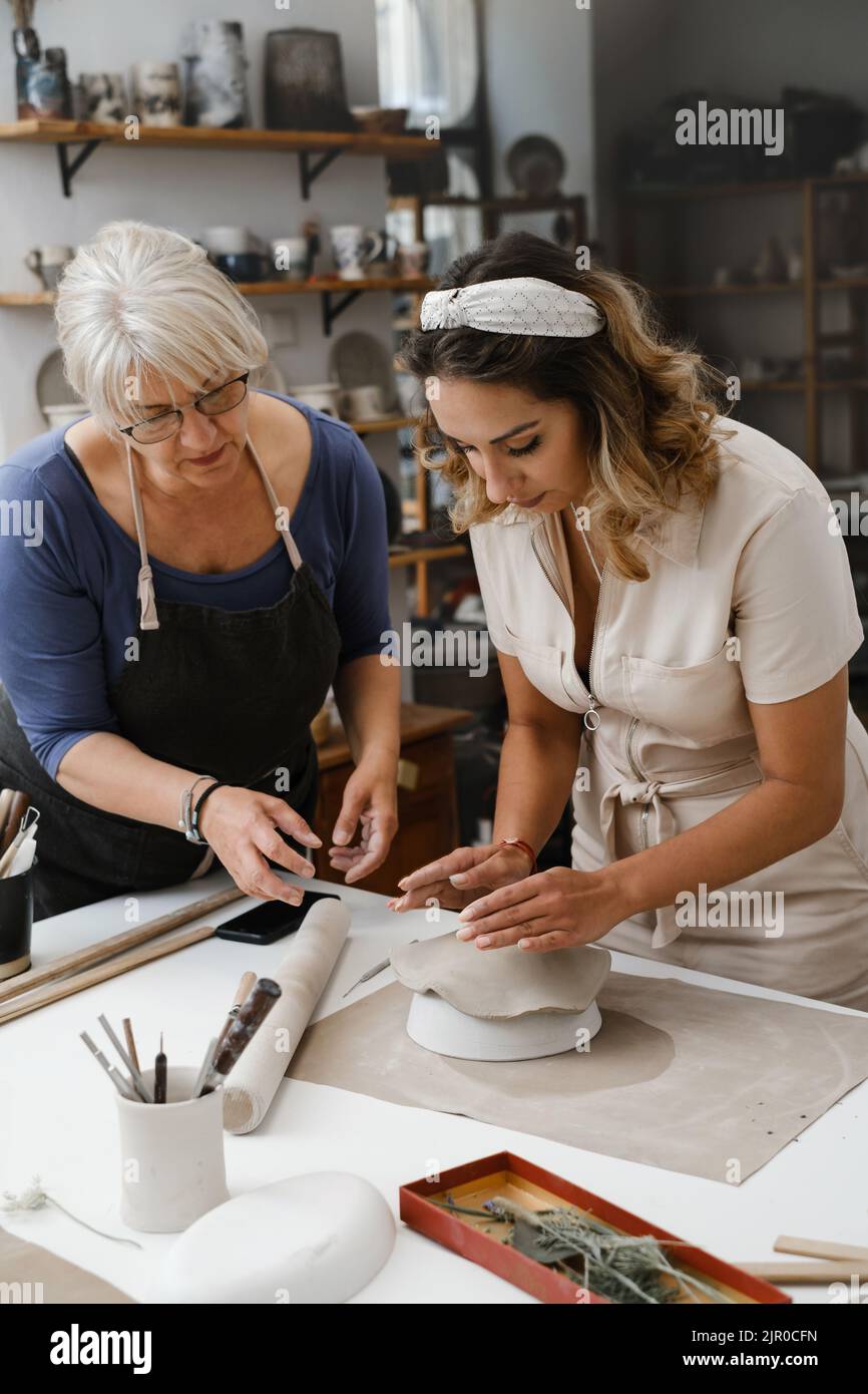 People working with clay on the table. Woman on pottery workshop in ...