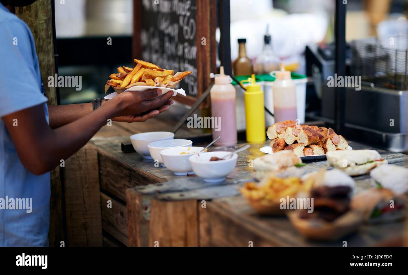 A black guy holding a plate of delicious french fries in a food market ...