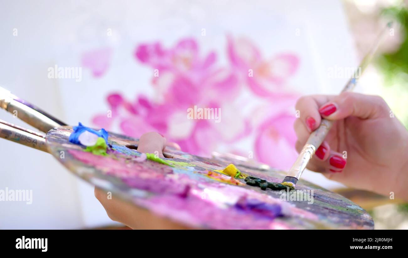close-up, female hands, painter, artist paints a picture of flowers ...