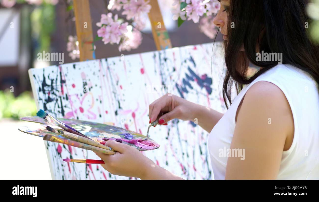 a beautiful woman painter in white dress, in blooming spring apple ...