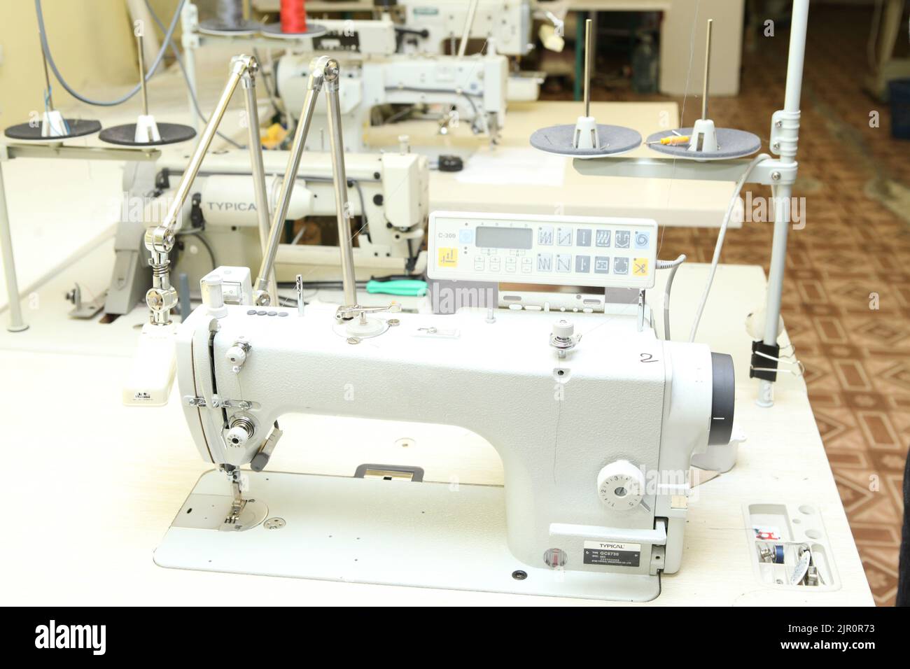 Shop for tailoring. A woman creates clothes on a sewing machine ...