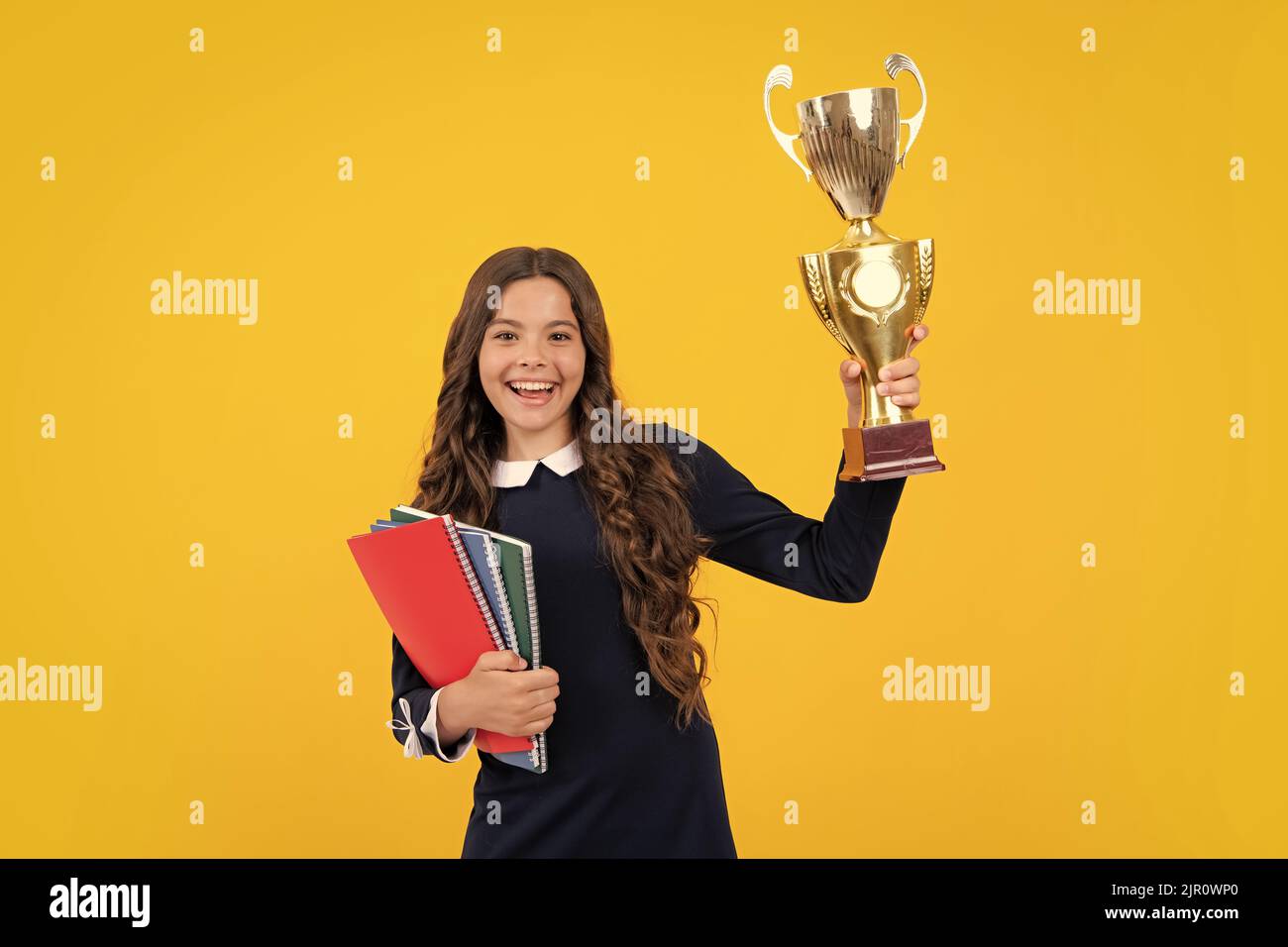Excited schoolgirl in school uniform celebrating victory with trophy ...
