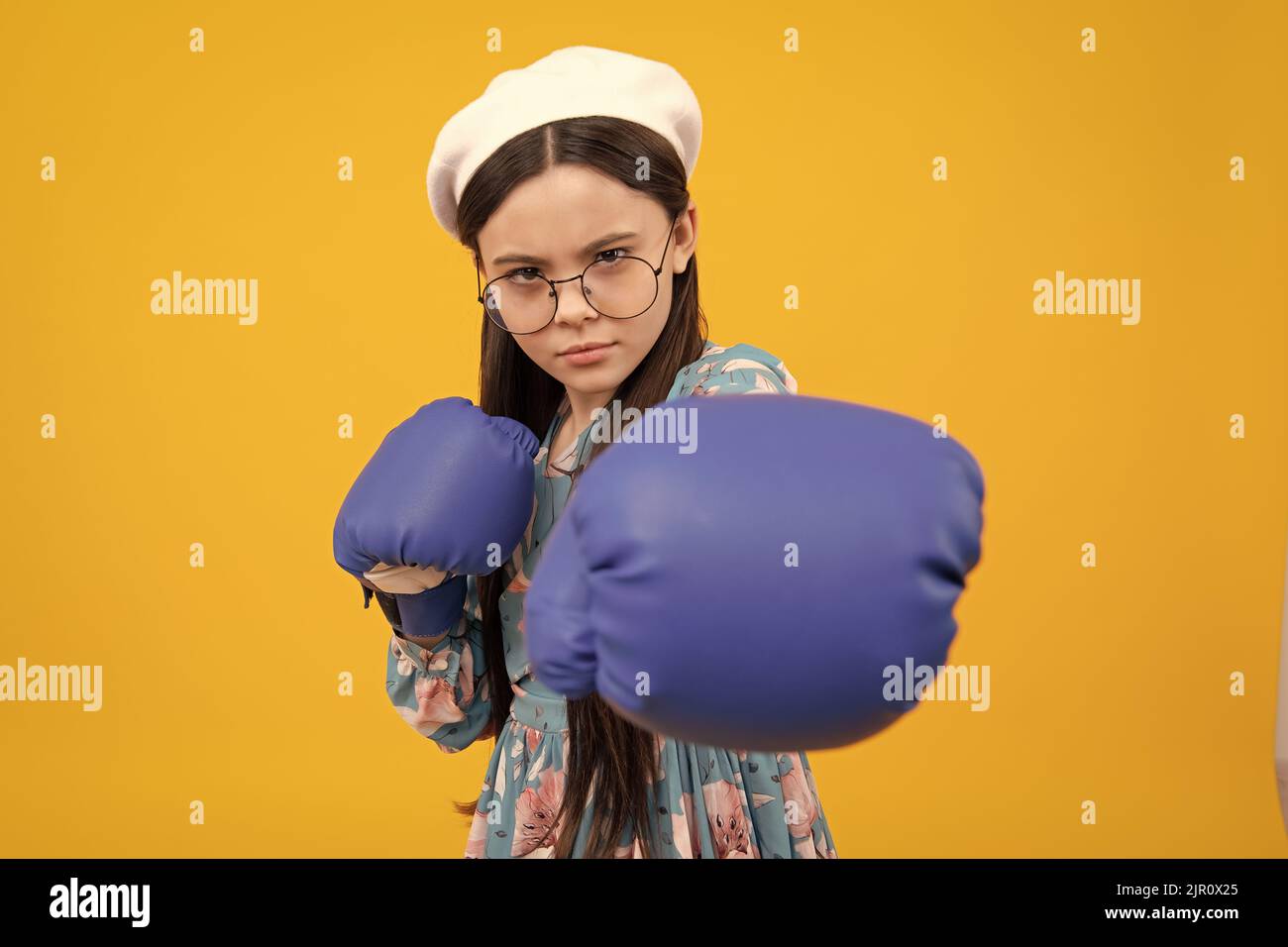 Portrait of a cute teenage boxer girl on yellow isolated background ...