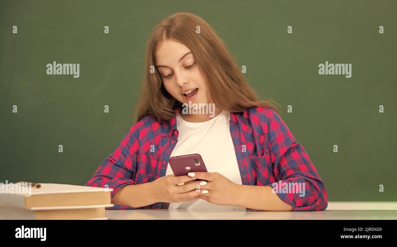 happy kid chatting on smartphone in classroom at blackboard, message ...