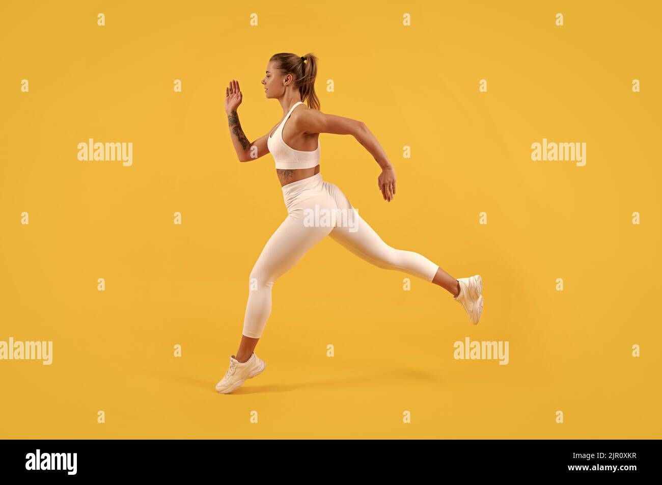 energetic sport woman runner running on yellow background Stock Photo ...