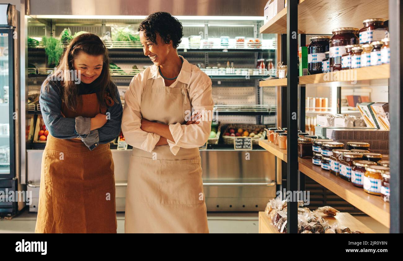 Two grocery store workers laughing happily while standing together in ...