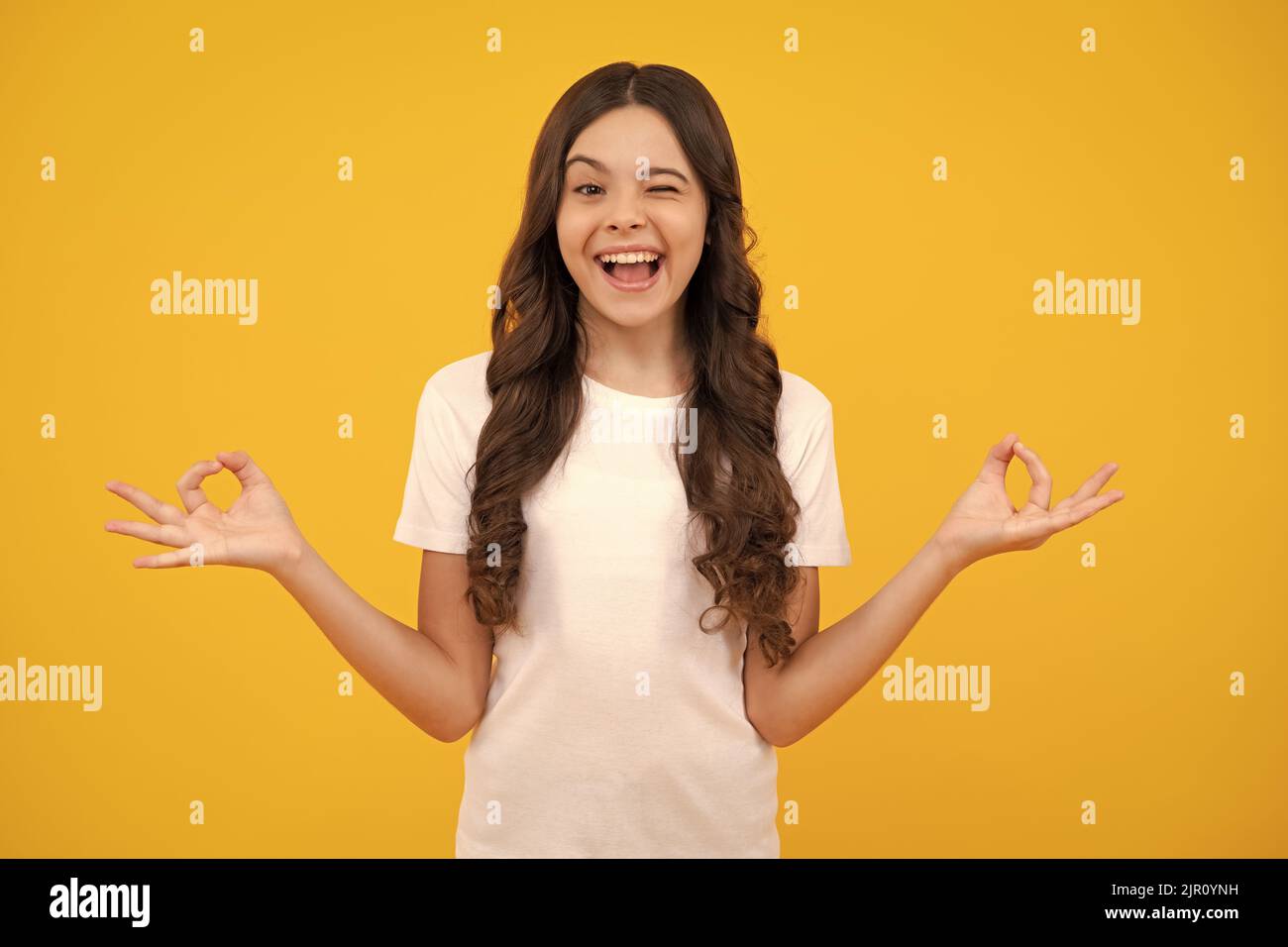 Funny winking teenager child girl in white shirt hold hands in yoga om ...