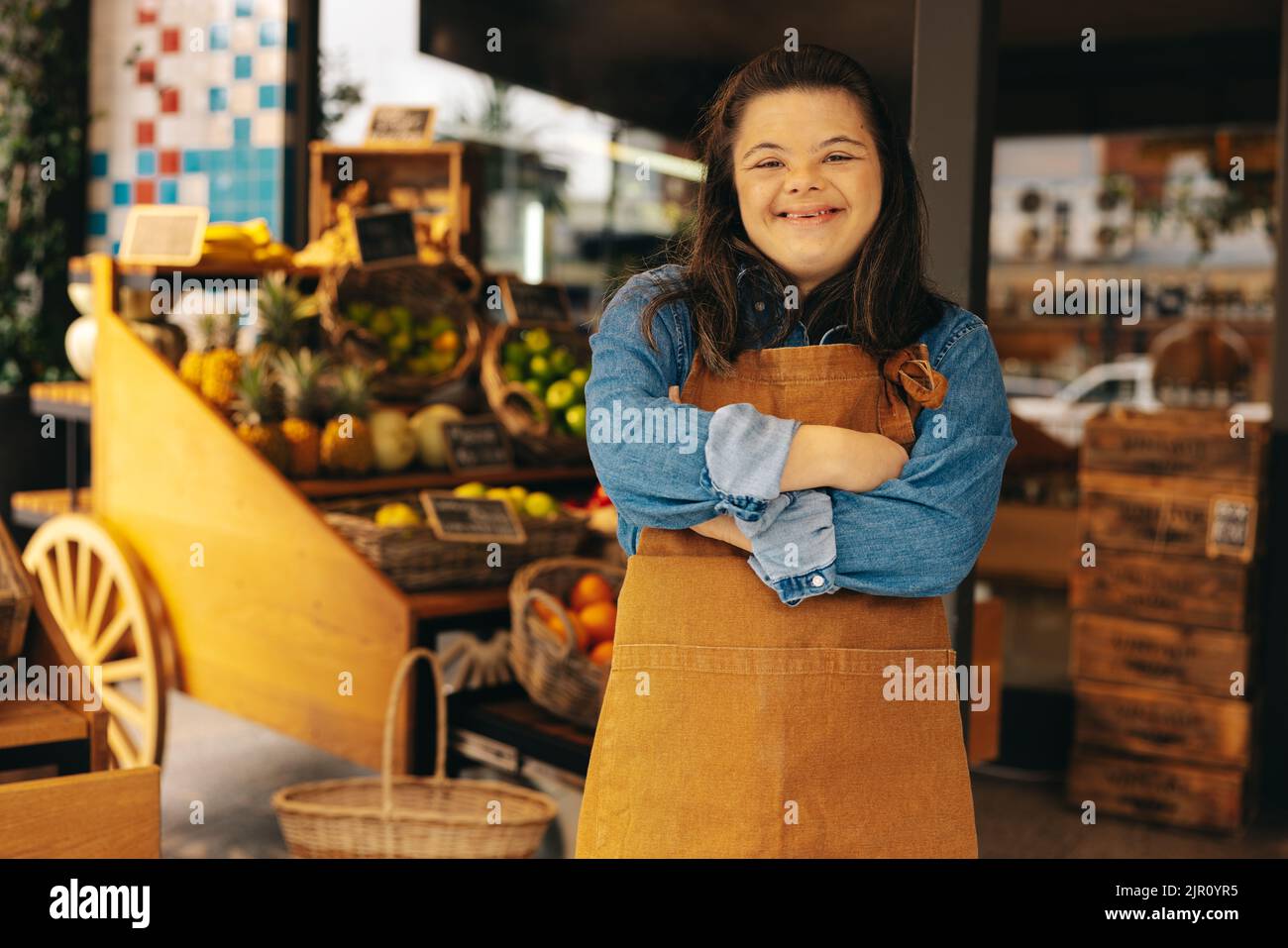 Cheerful shop employee with Down syndrome smiling at the camera while ...
