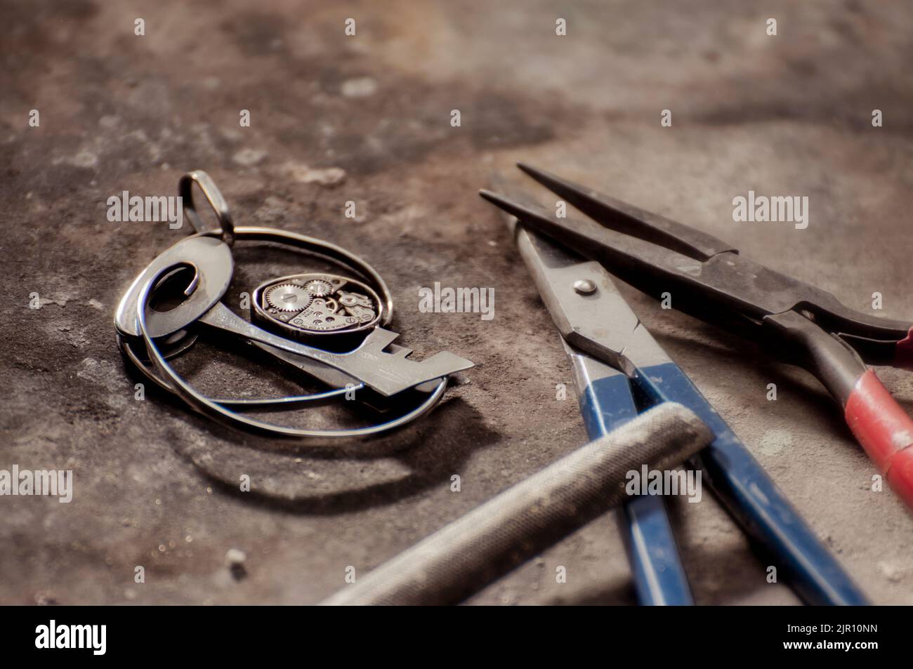 A closeup shot of pliers, other tools, and a key on a dusty surface ...