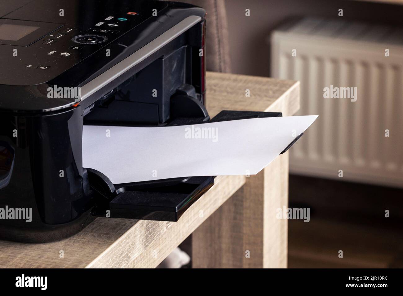A portrait of a printer with an blank white piece of paper in its printed output tray. The empty ...