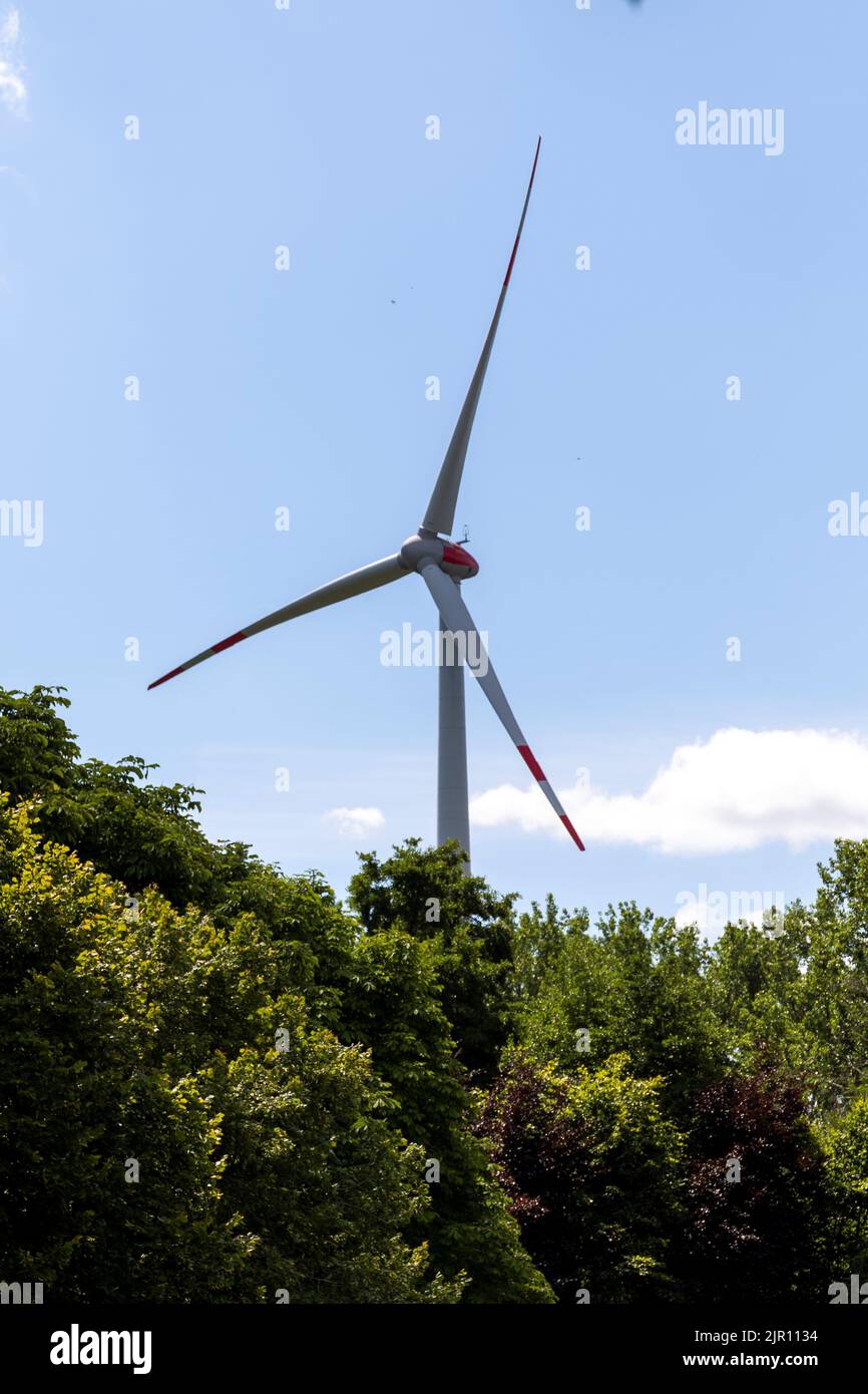 A vertical portrait of a windmill standing high above the trees in a ...