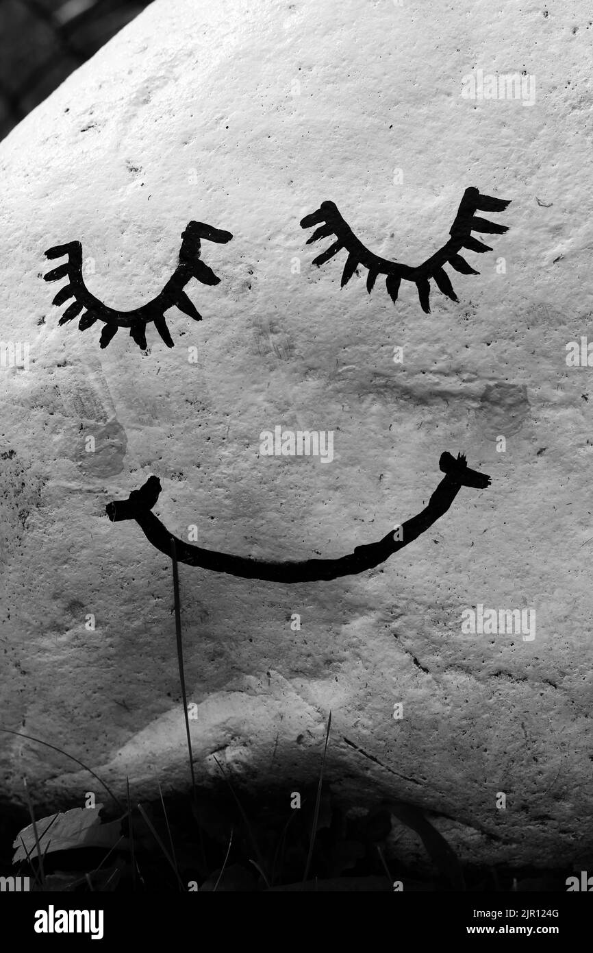 Happy smiley face painted on a garden rock as an inspirational message ...