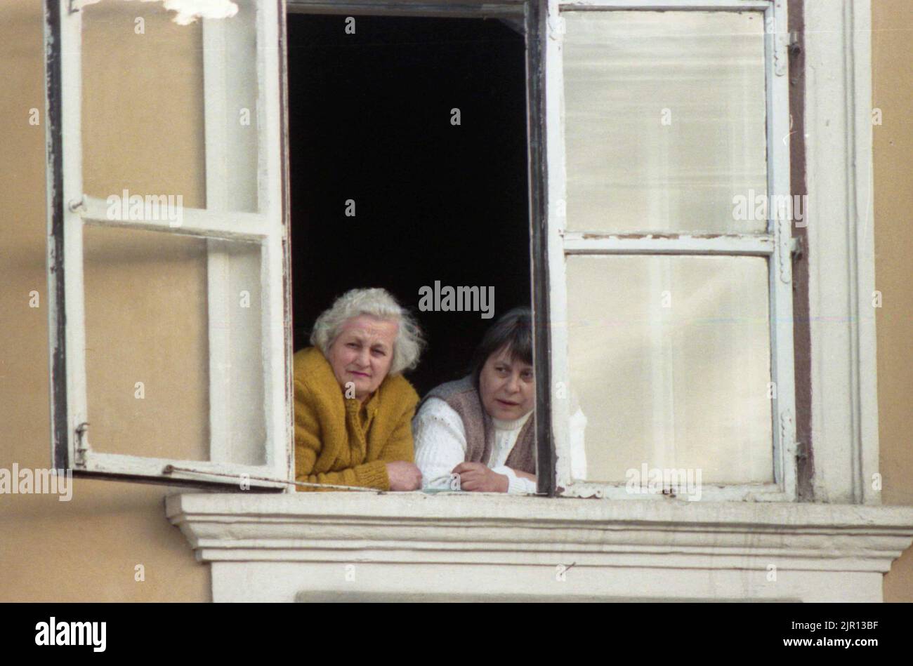 Brasov, Romania, 1990. Women looking out the window in the city center ...
