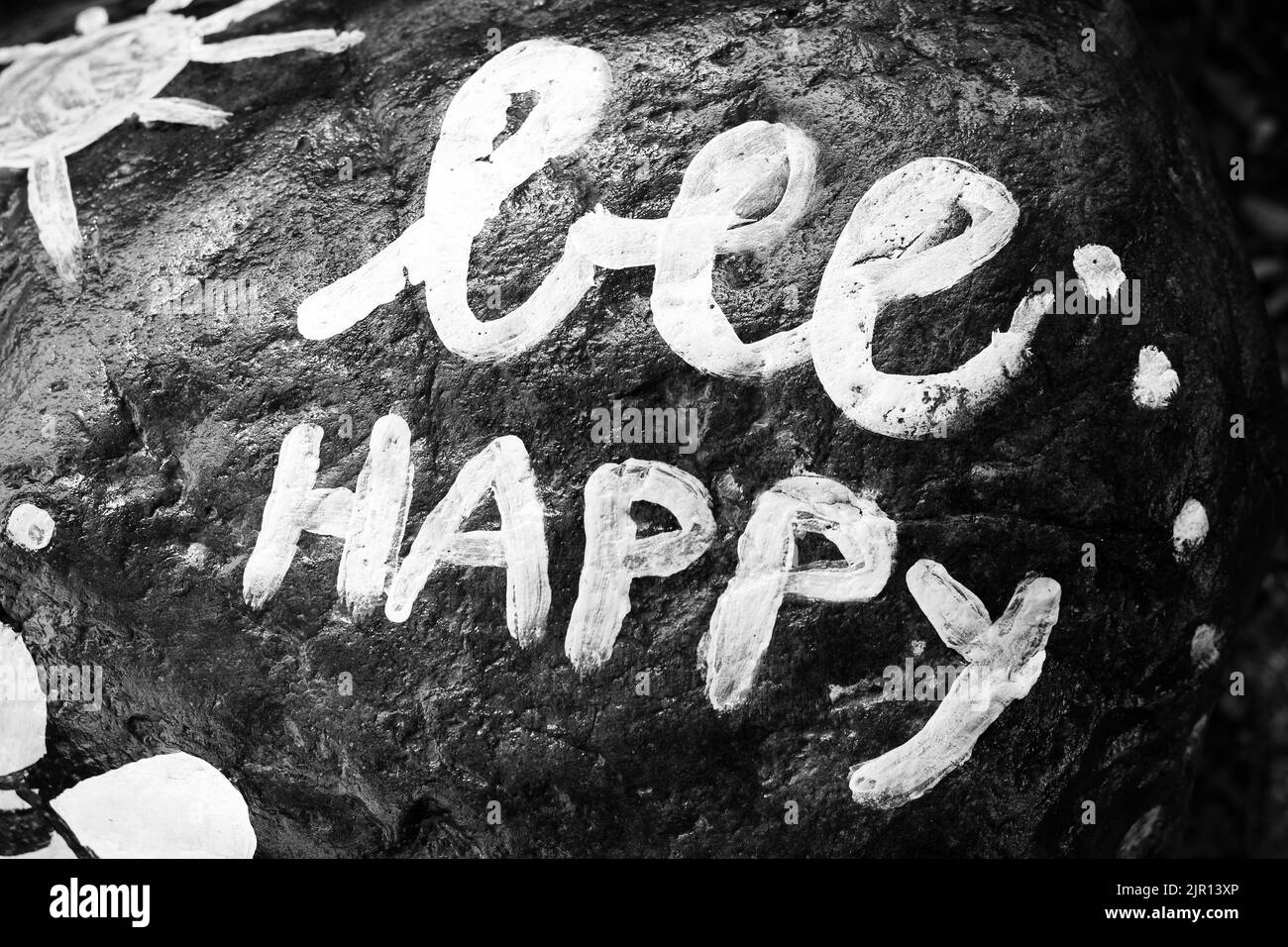 Bee happy painted on a rock as a summer garden decoration in black and ...