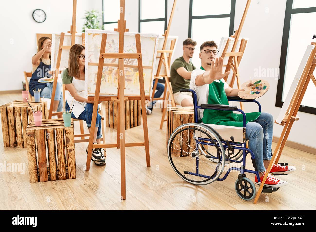 Young disabled man sitting on wheelchair drawing at art studio with ...