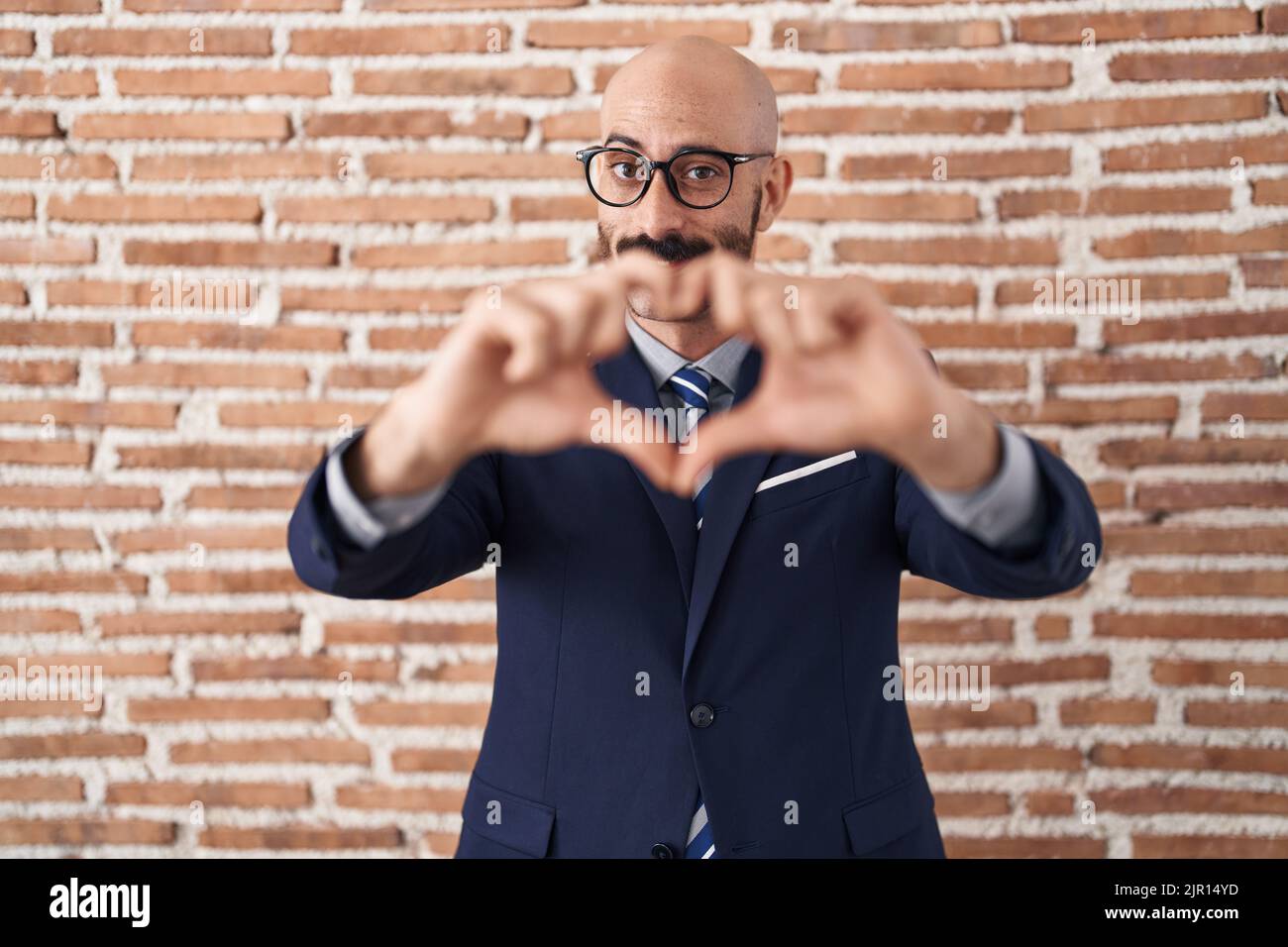 Bald man with beard wearing business clothes and glasses smiling in ...