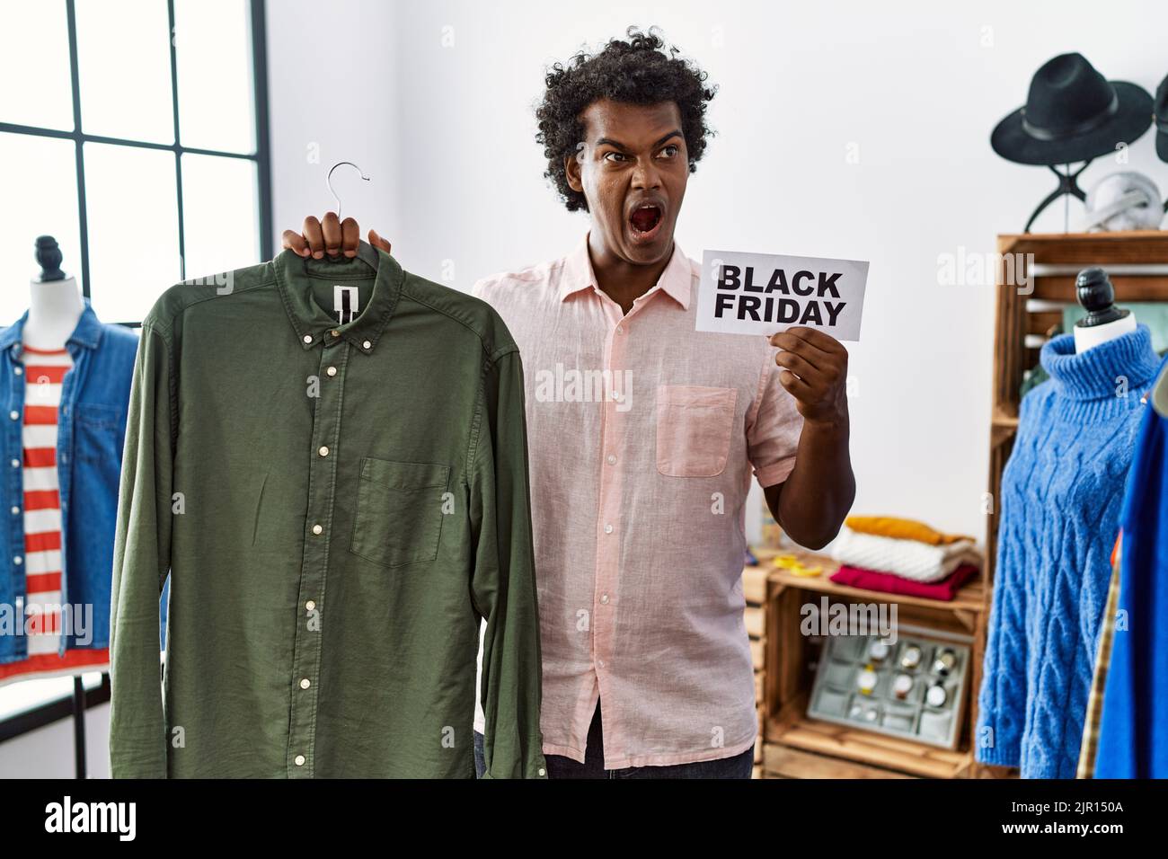 African man with curly hair holding black friday banner at retail shop ...
