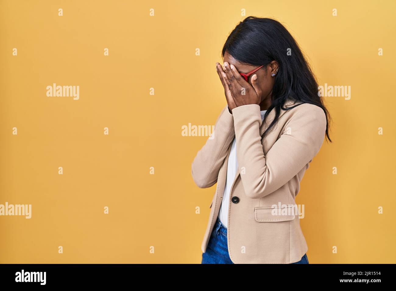 African young woman wearing glasses with sad expression covering face ...