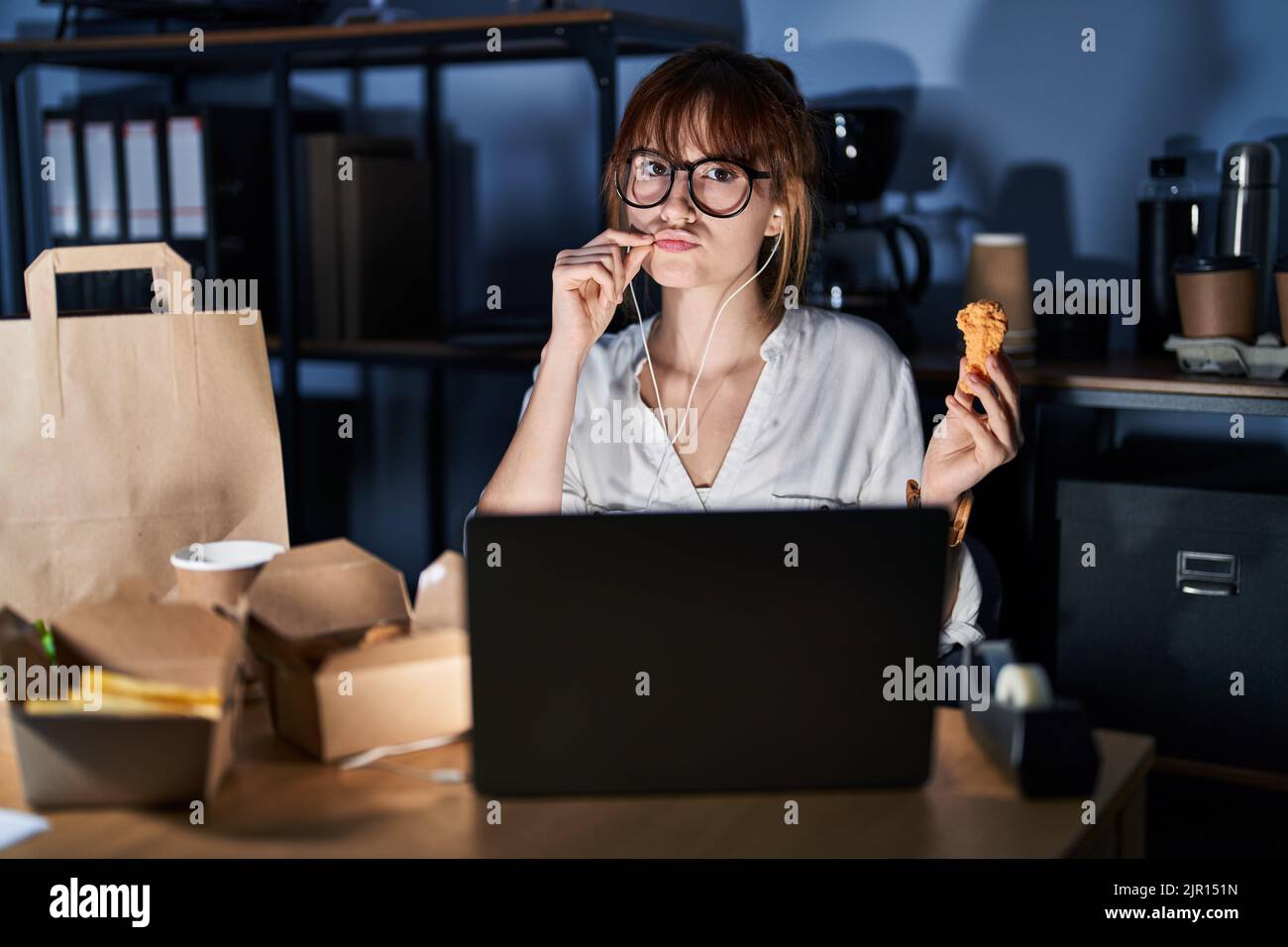 Young beautiful woman working using computer laptop and eating delivery ...