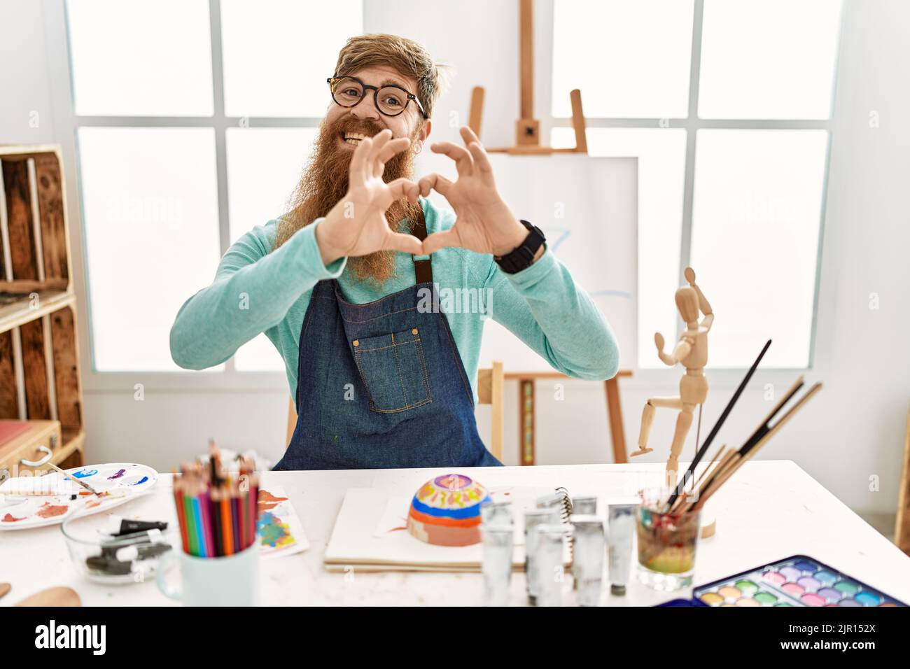 Redhead man with long beard painting clay bowl at art studio smiling in ...