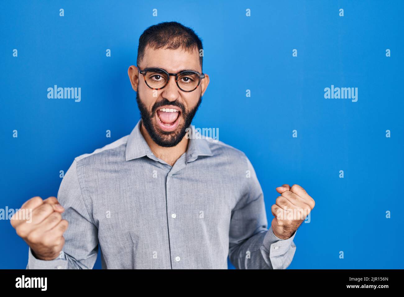 Middle east man with beard standing over blue background very happy and ...